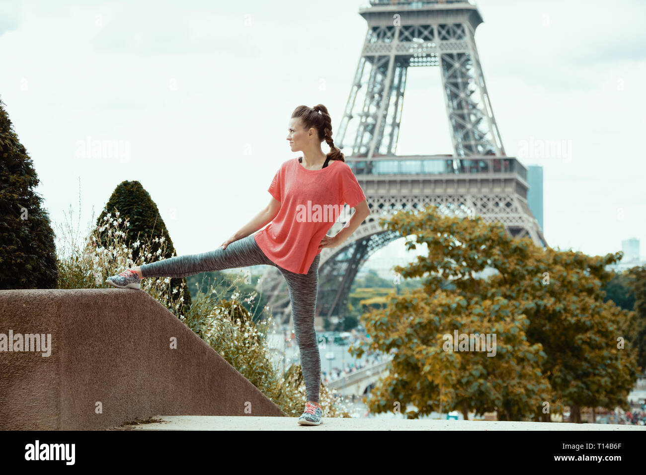 active sports woman in fitness clothes in the front of Eiffel tower in ...