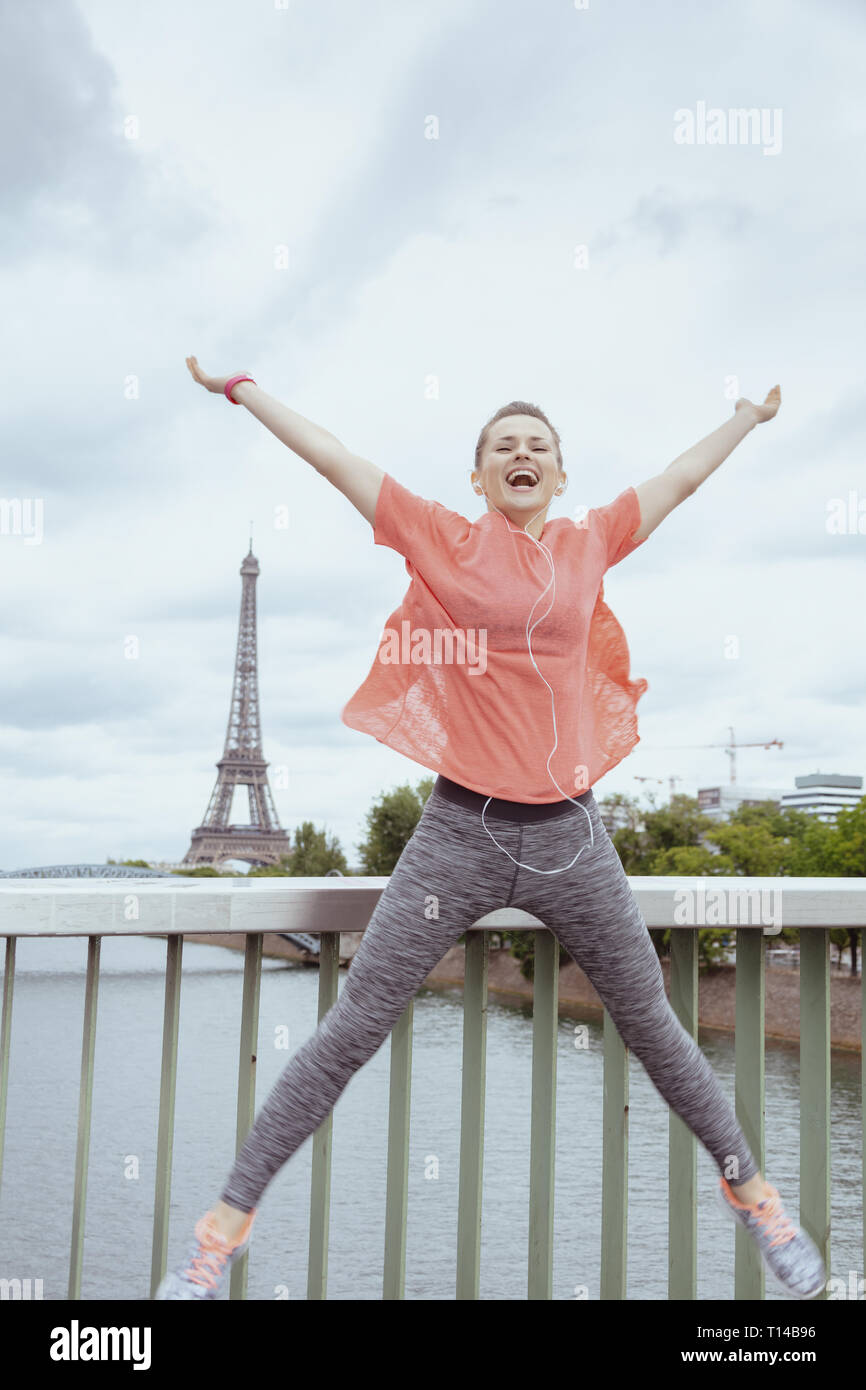 happy fit woman jogger in fitness clothes not far from Eiffel tower in ...
