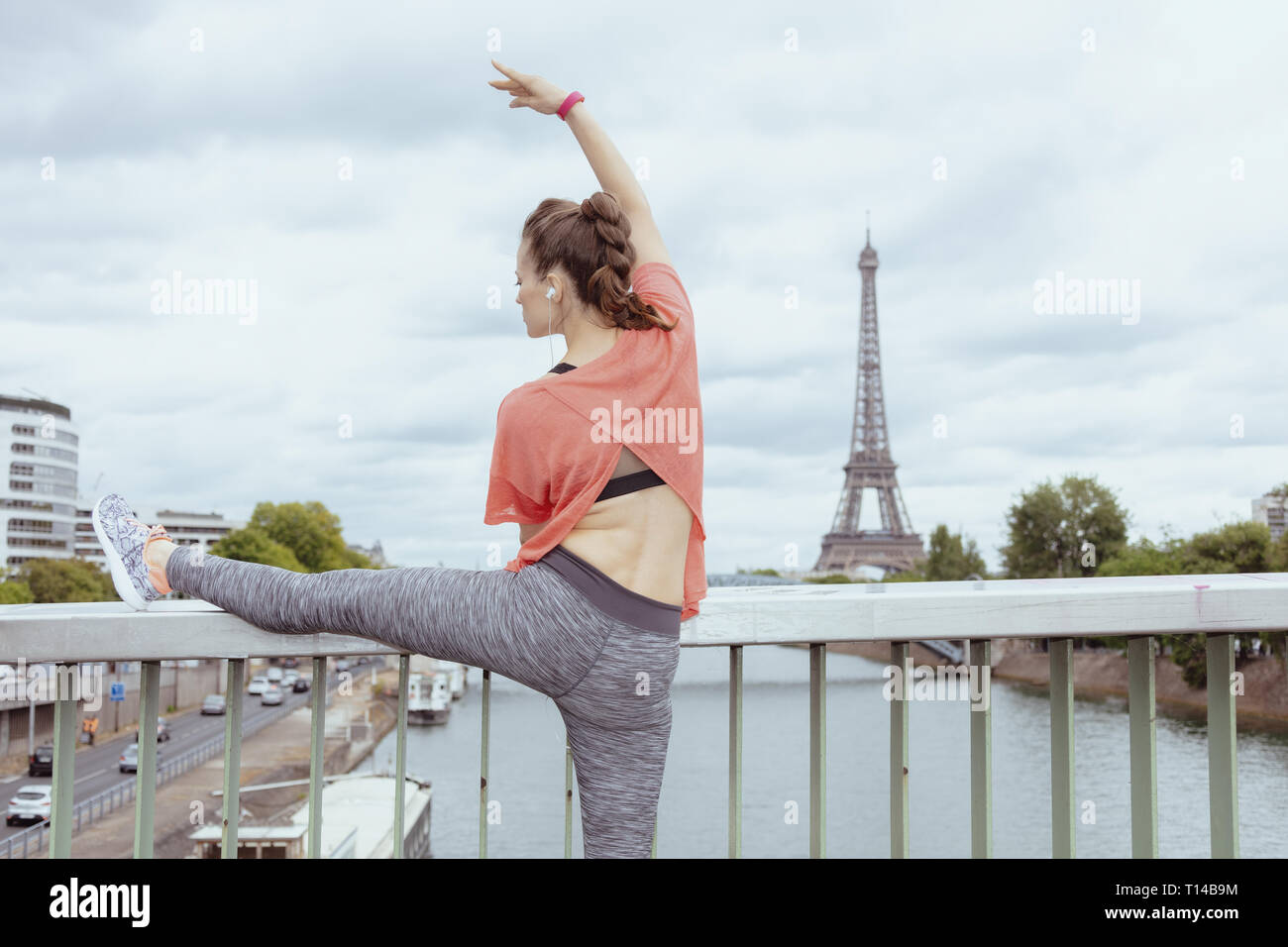 Seen from behind fit woman jogger in fitness clothes stretching against ...