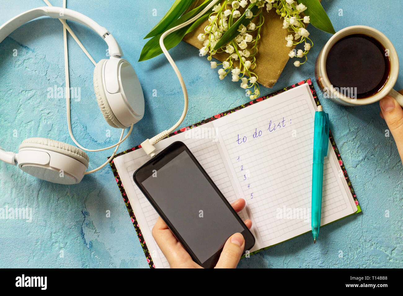 Smartphone in female hands and writing in notebook, lilies of the ...