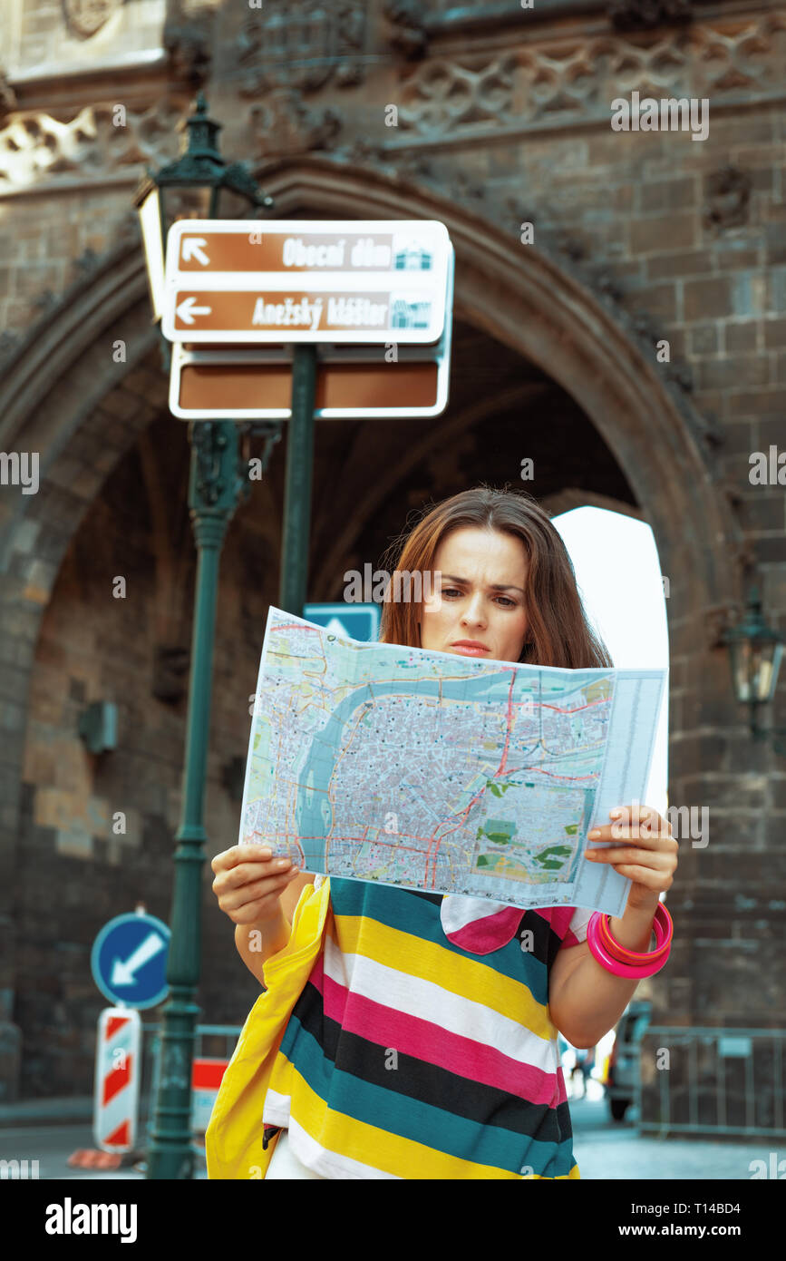 young woman in colorful striped t-shirt looking at the map against ...