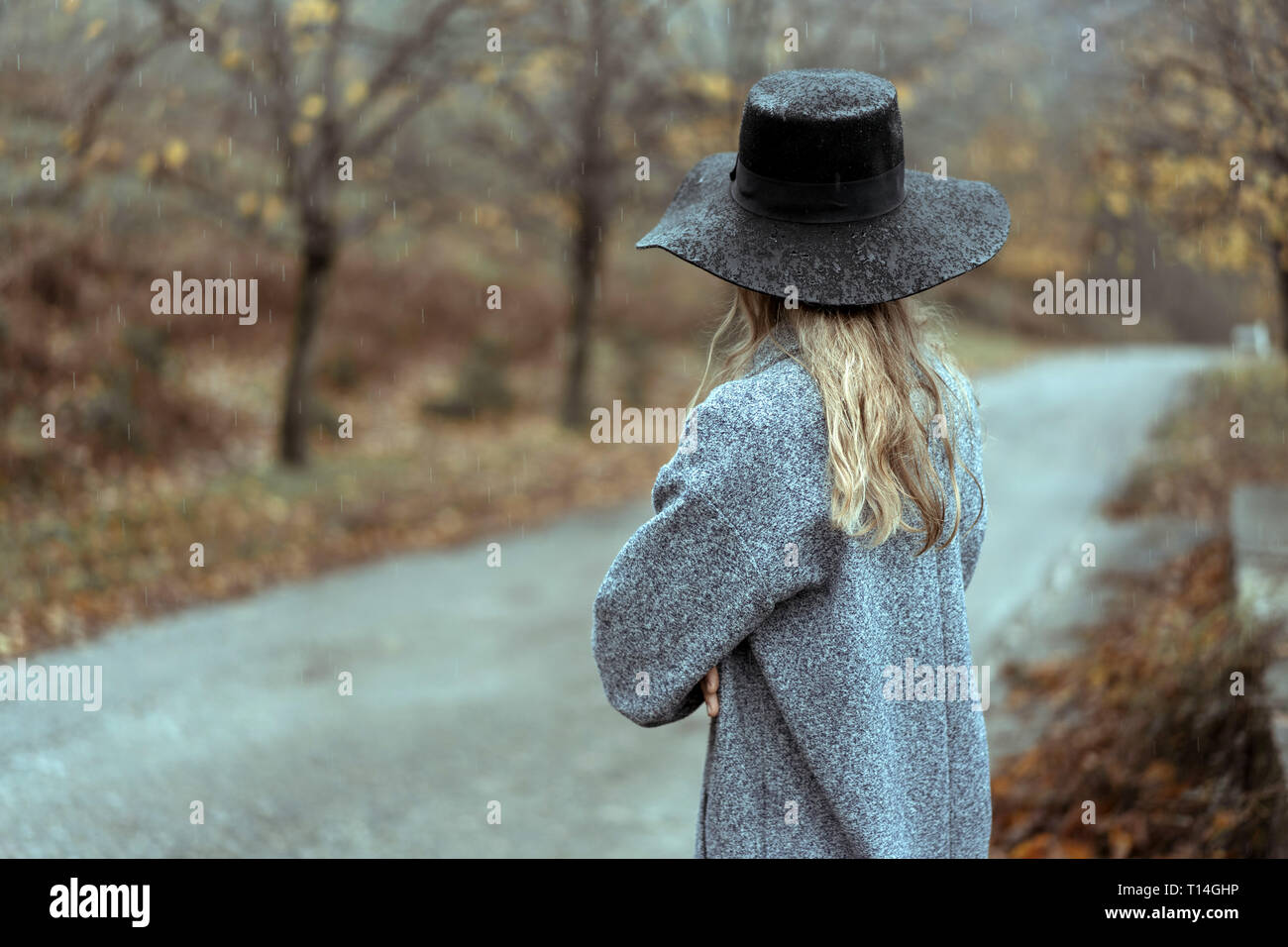 Girl in a hat on an autumn day is wet in the rain, sad and pensive mood ...