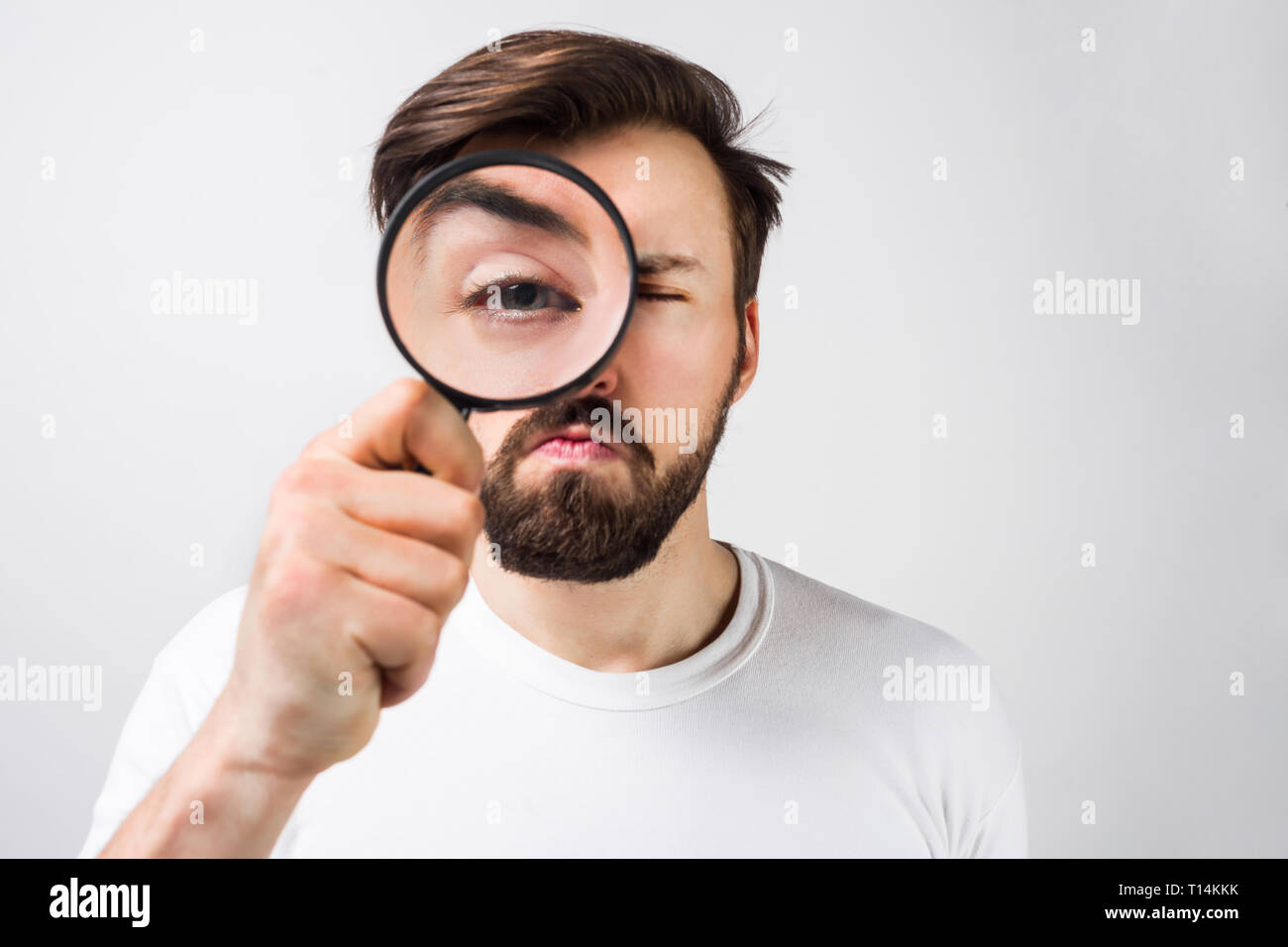 Close up of suspicious guy in white shirt looking straight ahead throu ...