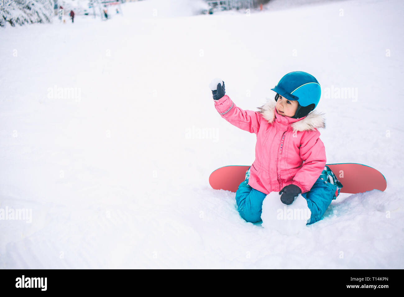 Snowboard Winter Sport. Little kid girl playing with snow wearing warm ...