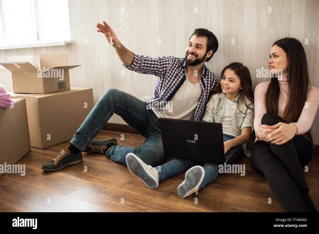 Happy family is looking somewhere aside. The man is showing something ...