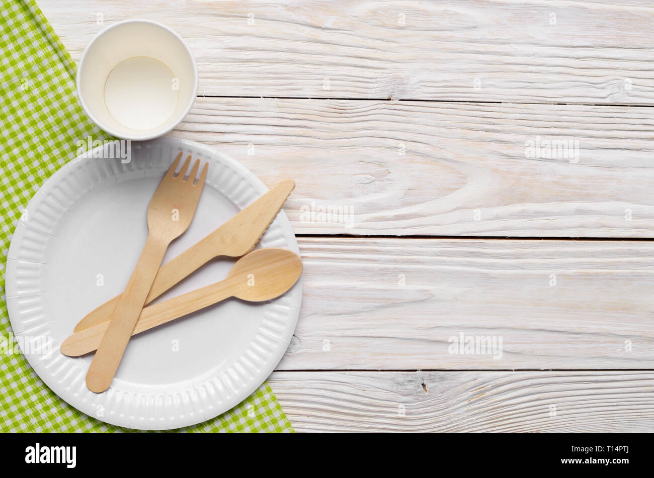 Wooden single use kitchenware in paper plate on table. Top view, space ...