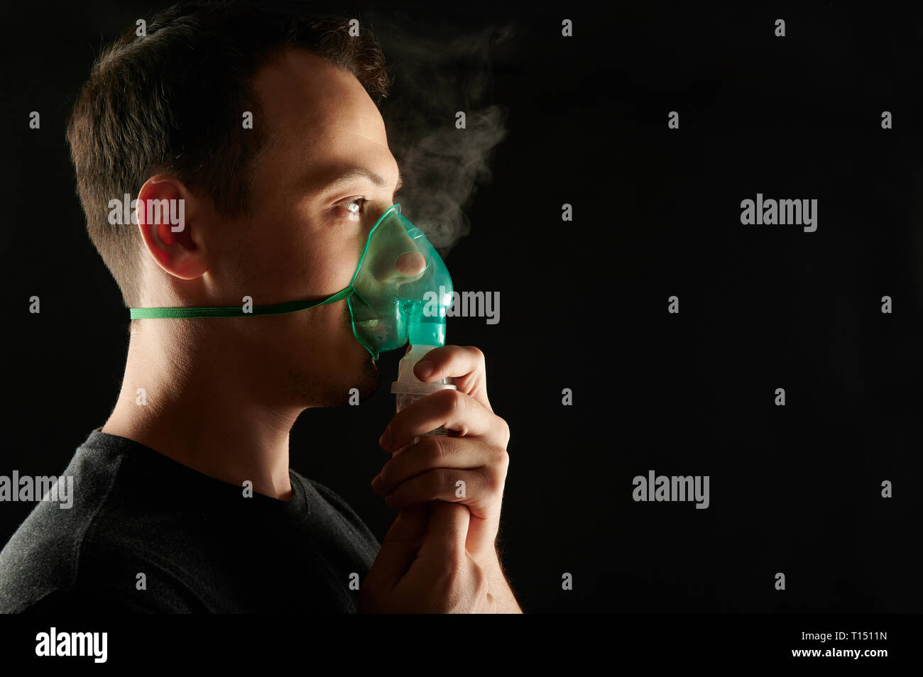 Profile portrait of man using nebulizer isolated on black background ...