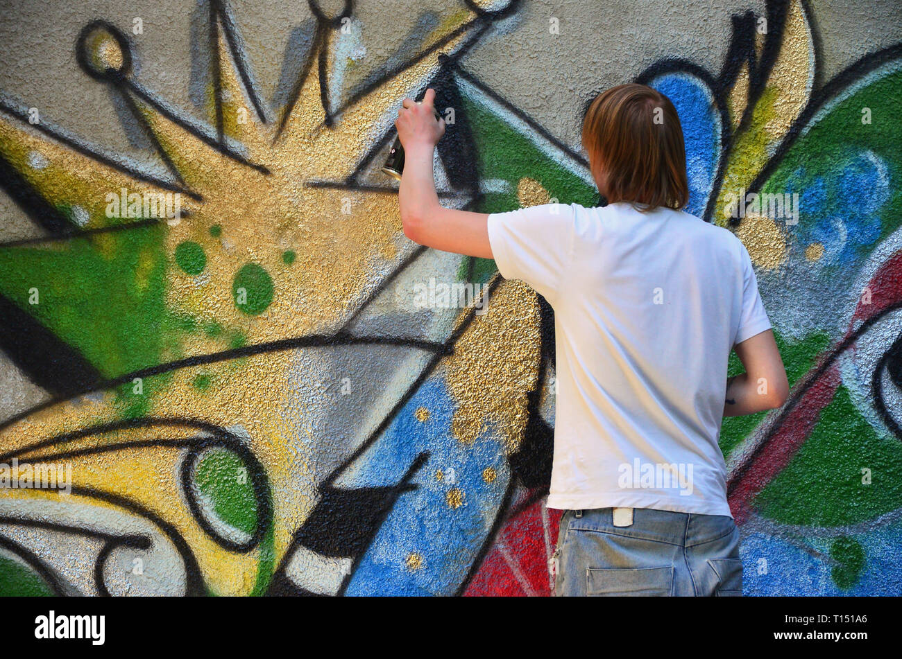 Photo of a young guy in denim shorts and a white shirt. The guy draws ...