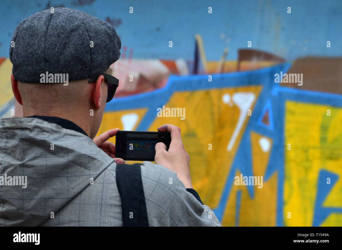 A young graffiti artist photographs his completed picture on the wall ...