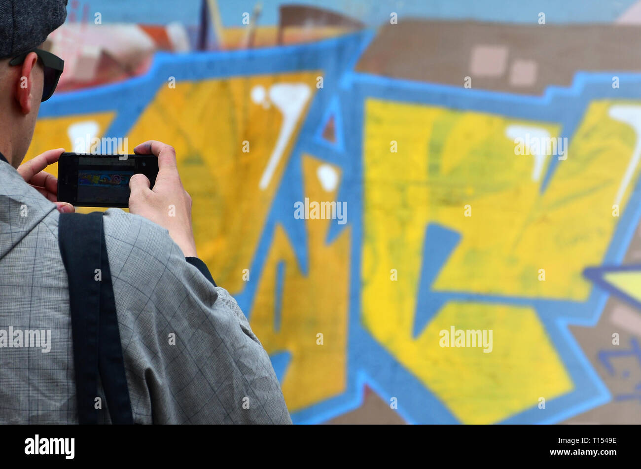 A young graffiti artist photographs his completed picture on the wall ...
