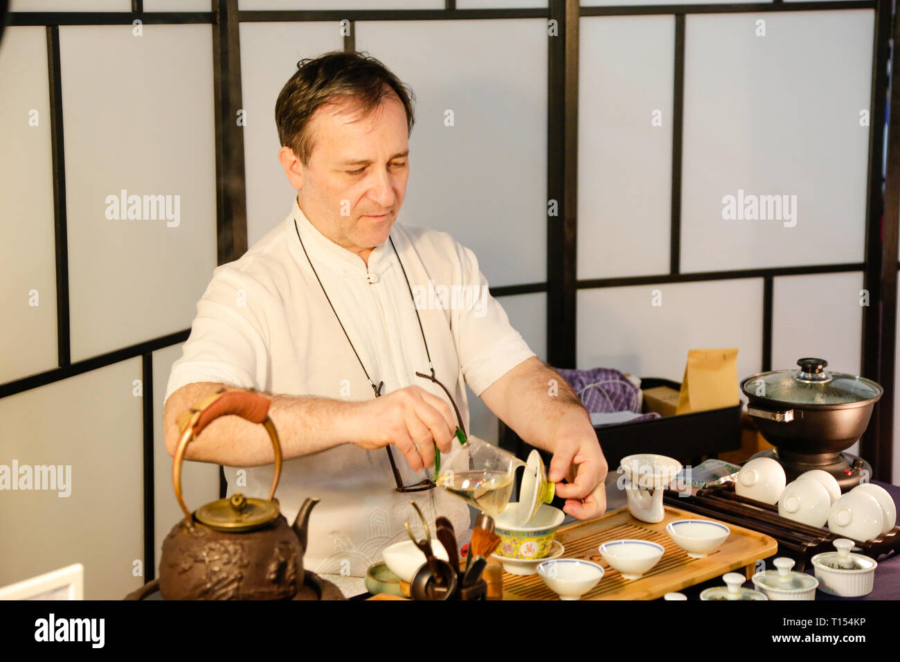 Elegant man in white suit offers relaxing moments through cups of ...