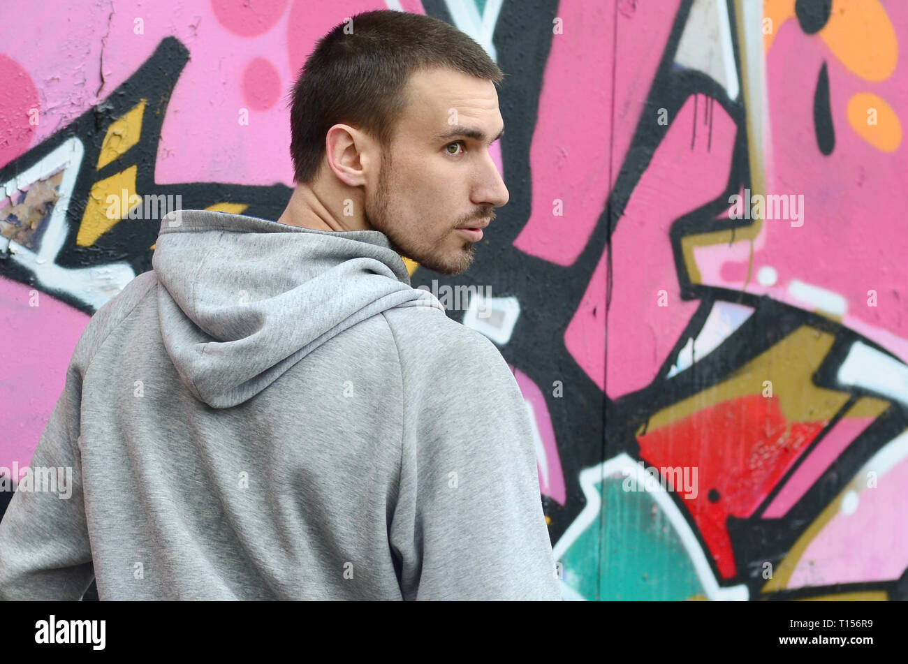 A young graffiti artist looks around while drawing. Vandal tries to be ...