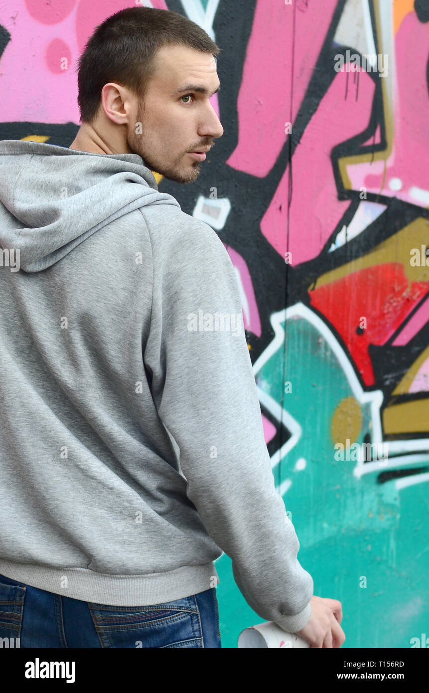 A young graffiti artist looks around while drawing. Vandal tries to be ...