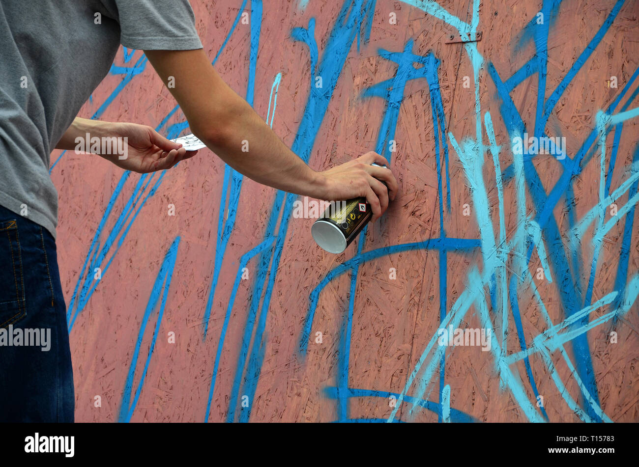 A young graffiti artist paints a new graffiti on the wall. Photo of the ...