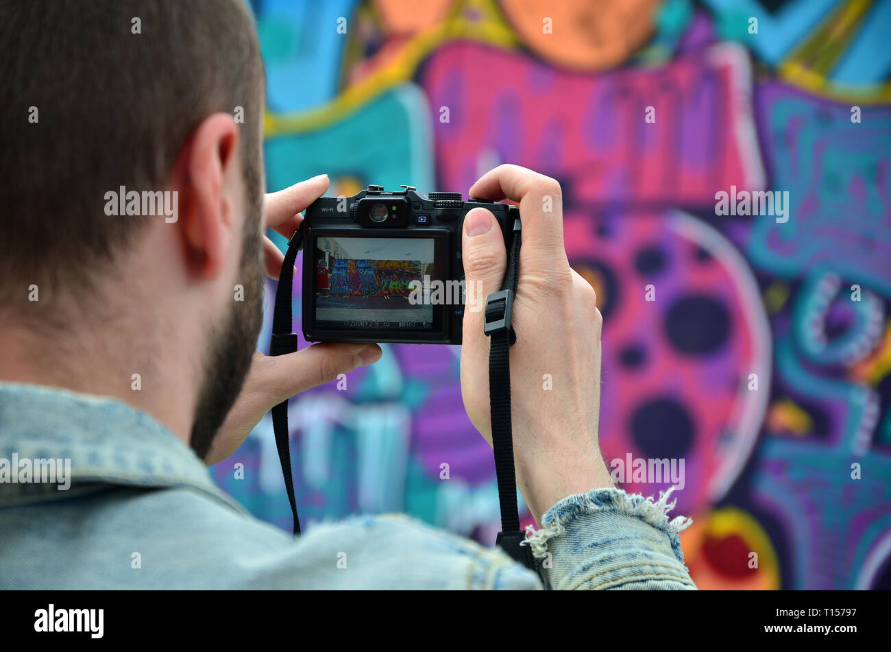 A young graffiti artist photographs his completed picture on the wall ...