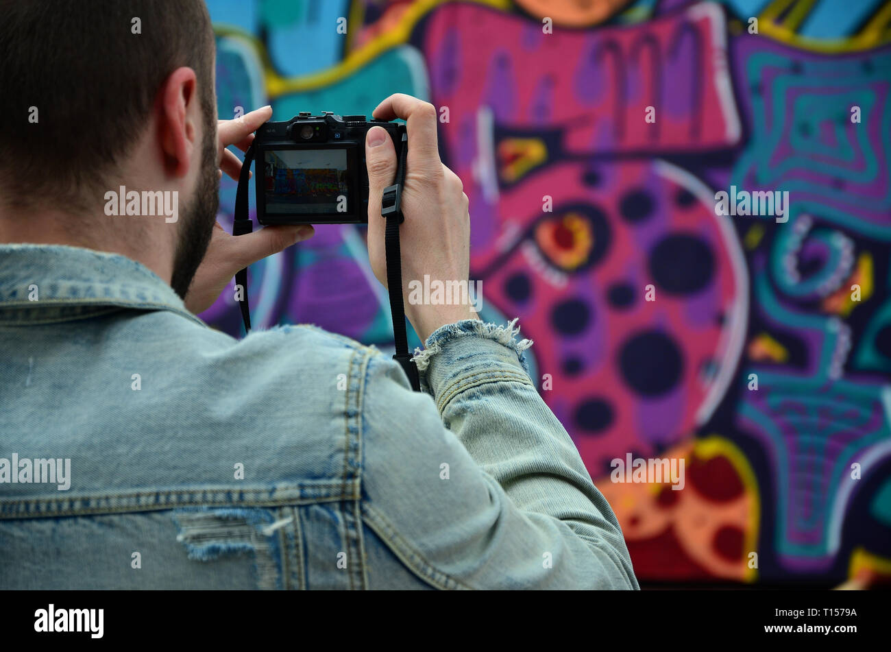 A young graffiti artist photographs his completed picture on the wall ...