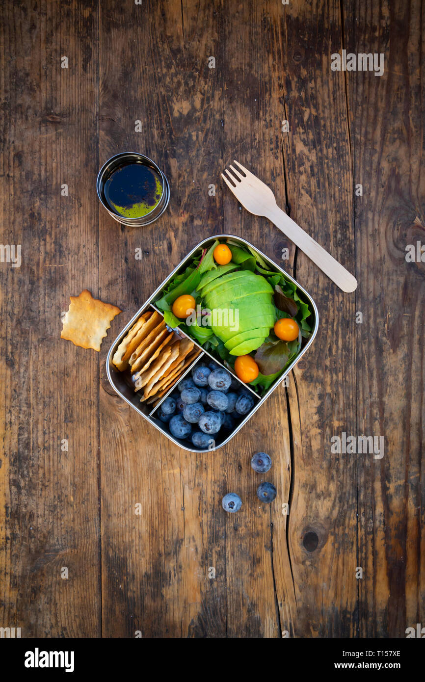 Lunch box of leaf salad, avocado, blueberries, tomatoes and crackers ...