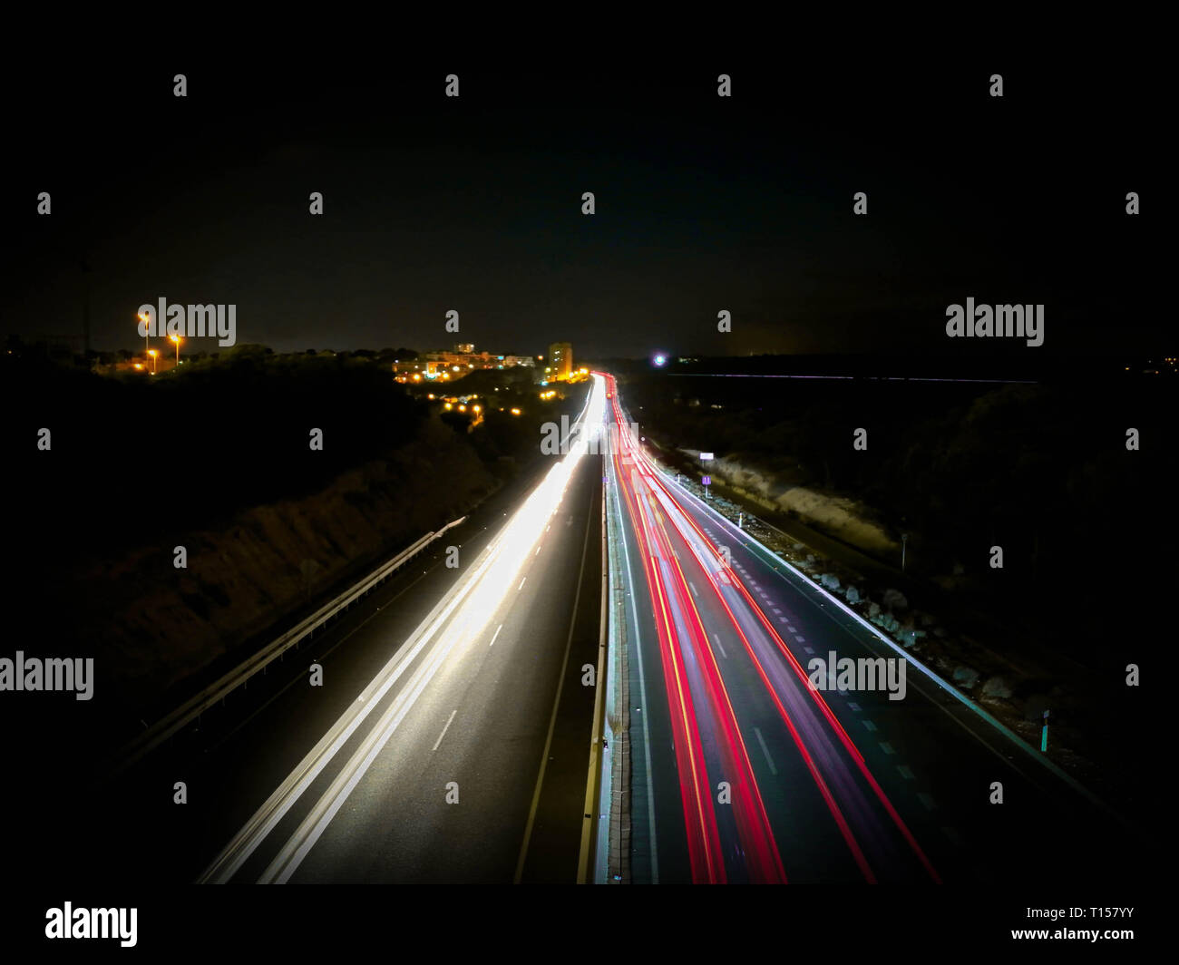 Car lights on a highway and transmission tower at night, long exposure ...