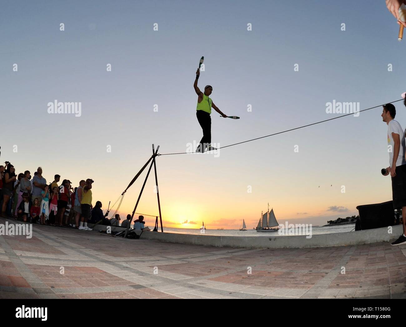 Male street performer balancing on tightrope while juggling, entertain ...