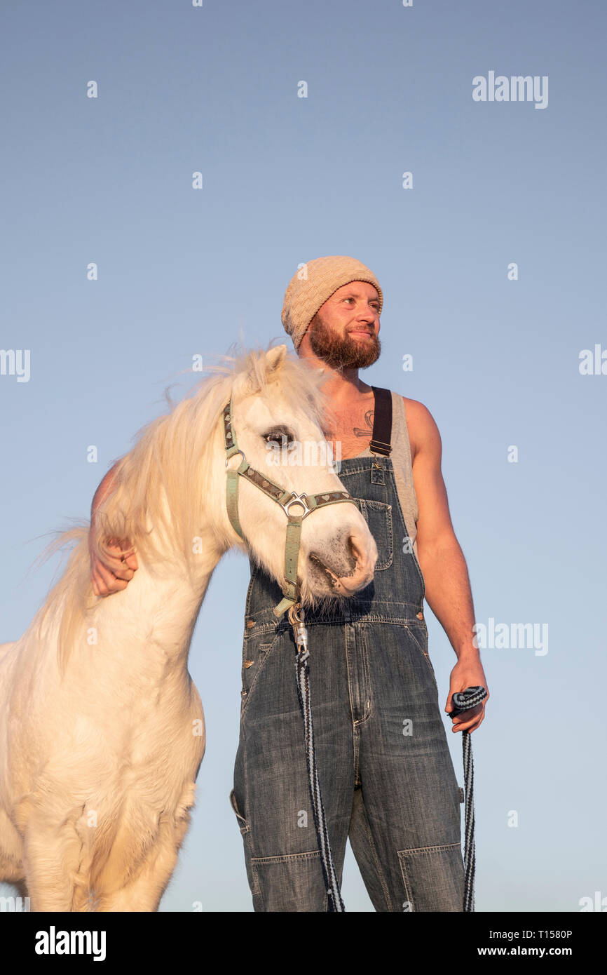 Smiling man with pony under blue sky Stock Photo - Alamy