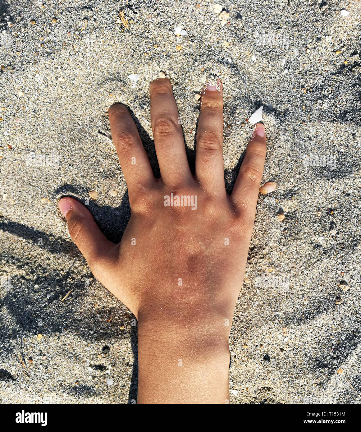 Woman's hand making a drawing in the sand with her hand extended during ...