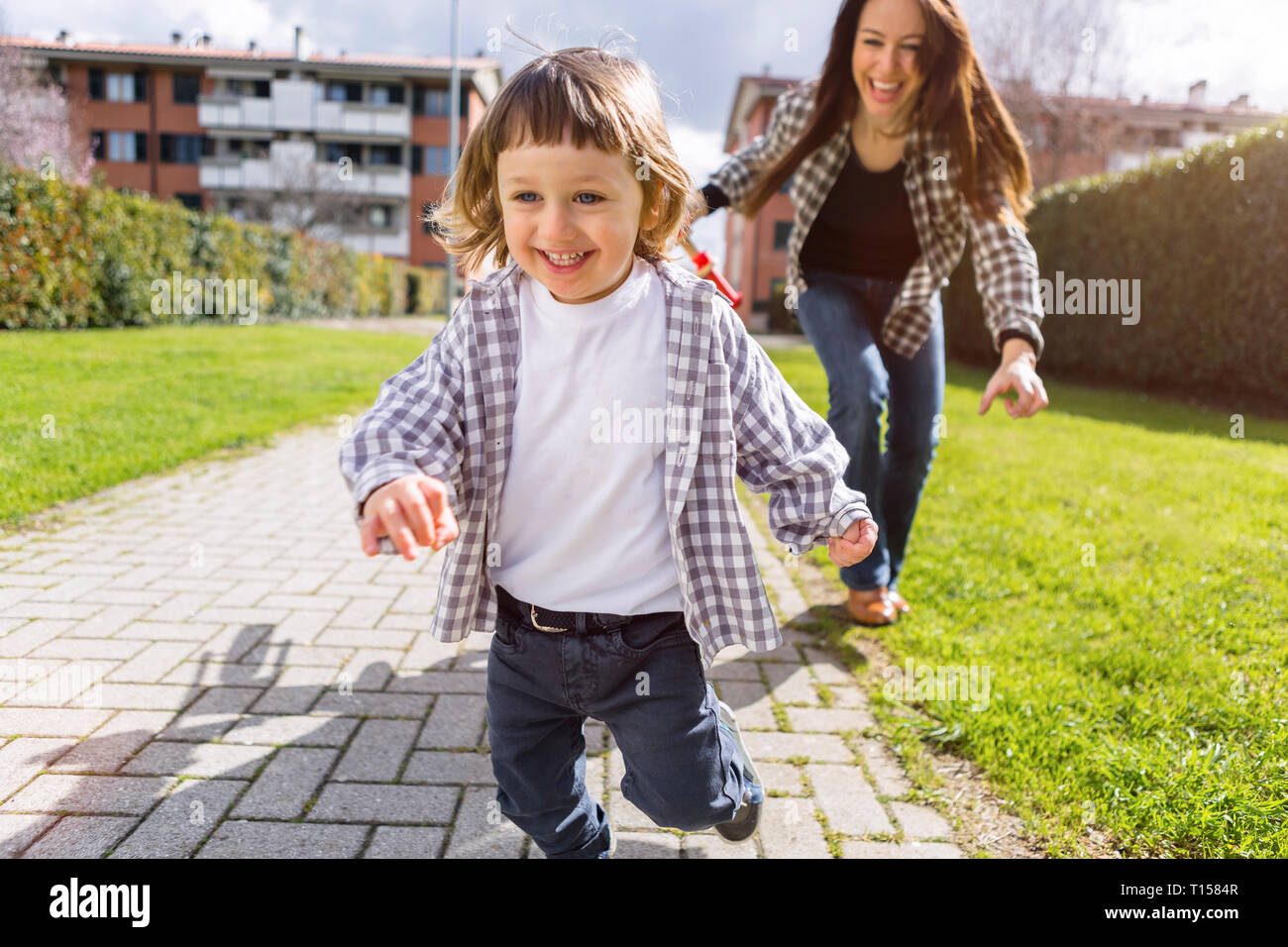 Mother running behind happy toddler son on a path Stock Photo - Alamy