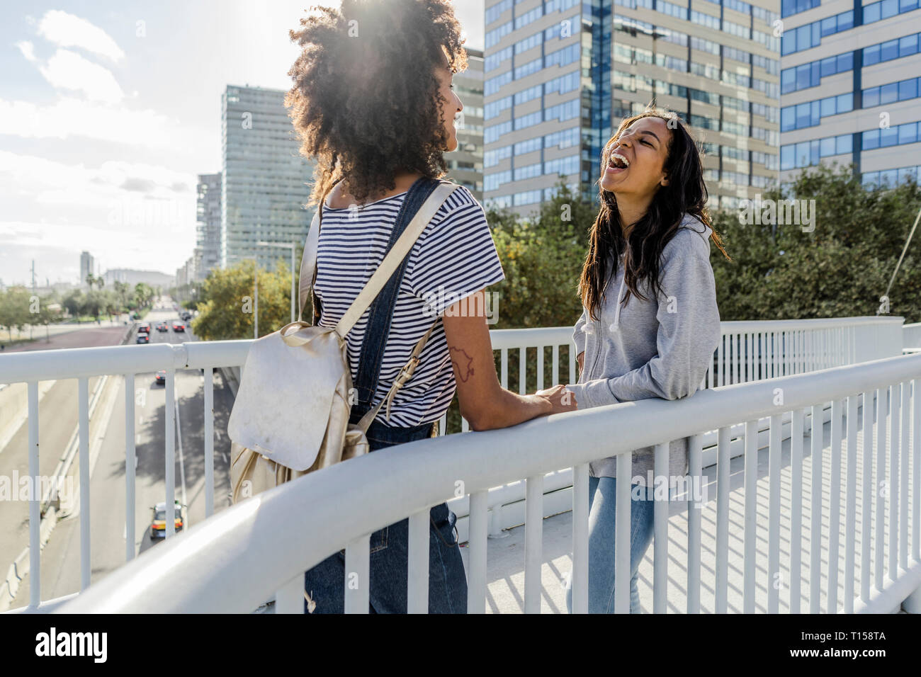 Girl friends meeting on a bridge, having fun Stock Photo - Alamy