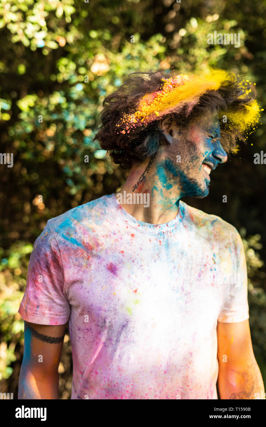Man shaking his head, full of colorful powder paint, celebrating Holi ...