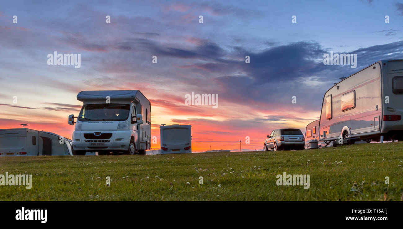 Camping caravans and cars parked on a grassy campground under beautiful ...