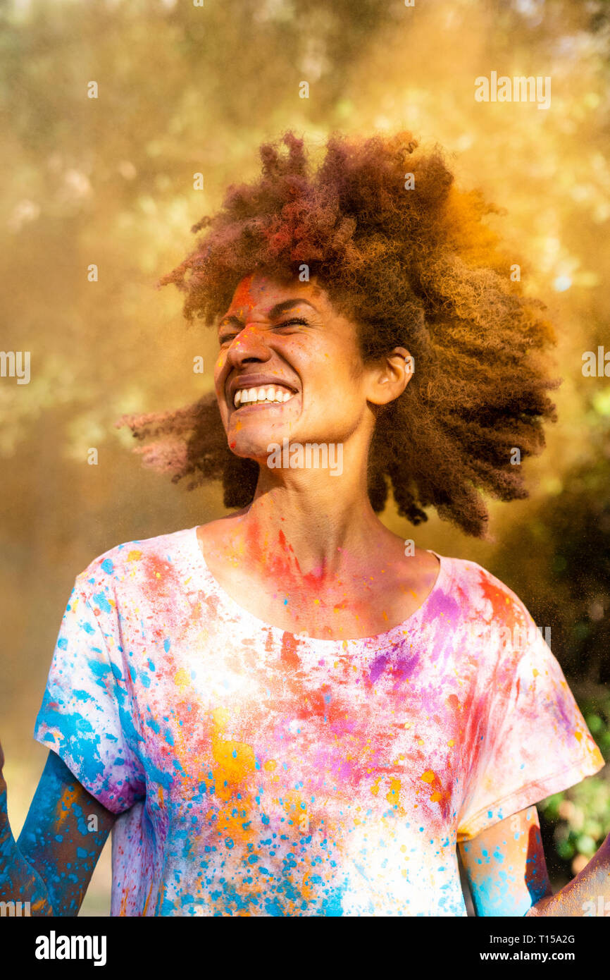Woman shaking her head, full of colorful powder paint, celebrating Holi ...