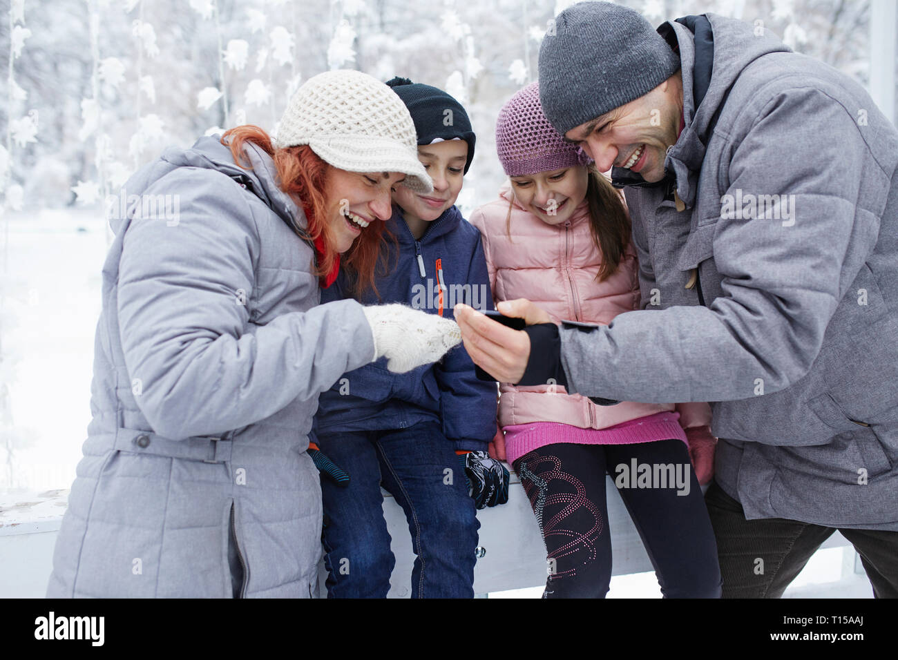 Family with two kids on the ice rink, looking at selfies on their ...
