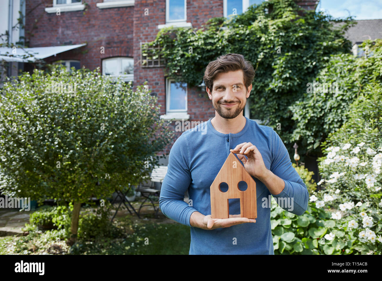 Portrait of smiling man in front of his home holding house model Stock ...