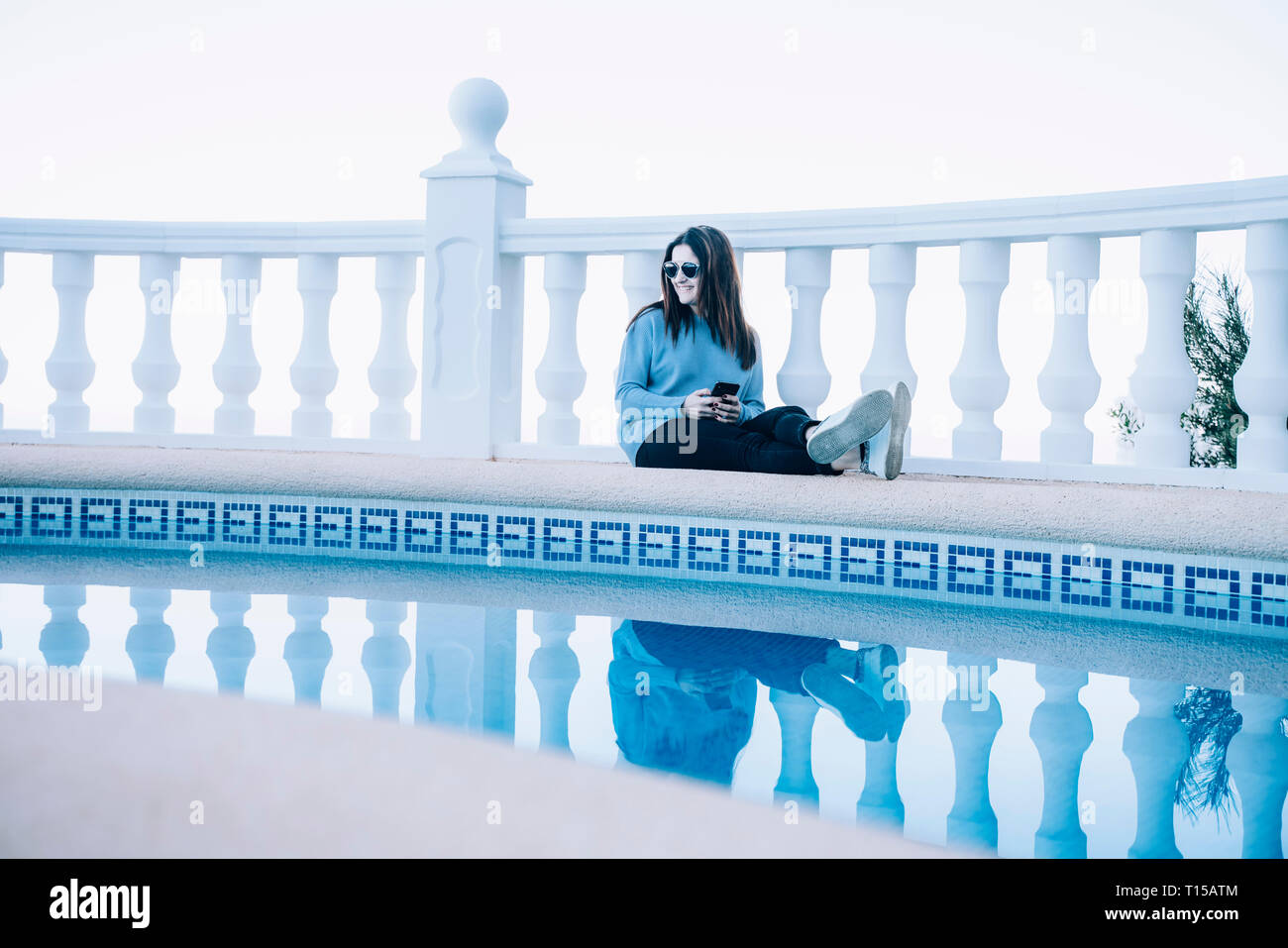 Woman with smartphone at swimming pool Stock Photo - Alamy