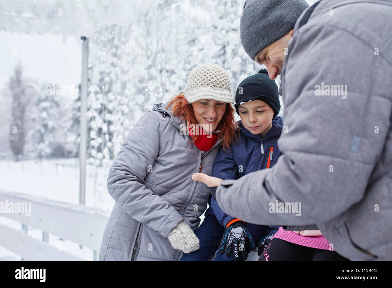 Family with two kids on the ice rink, looking at selfies on their ...