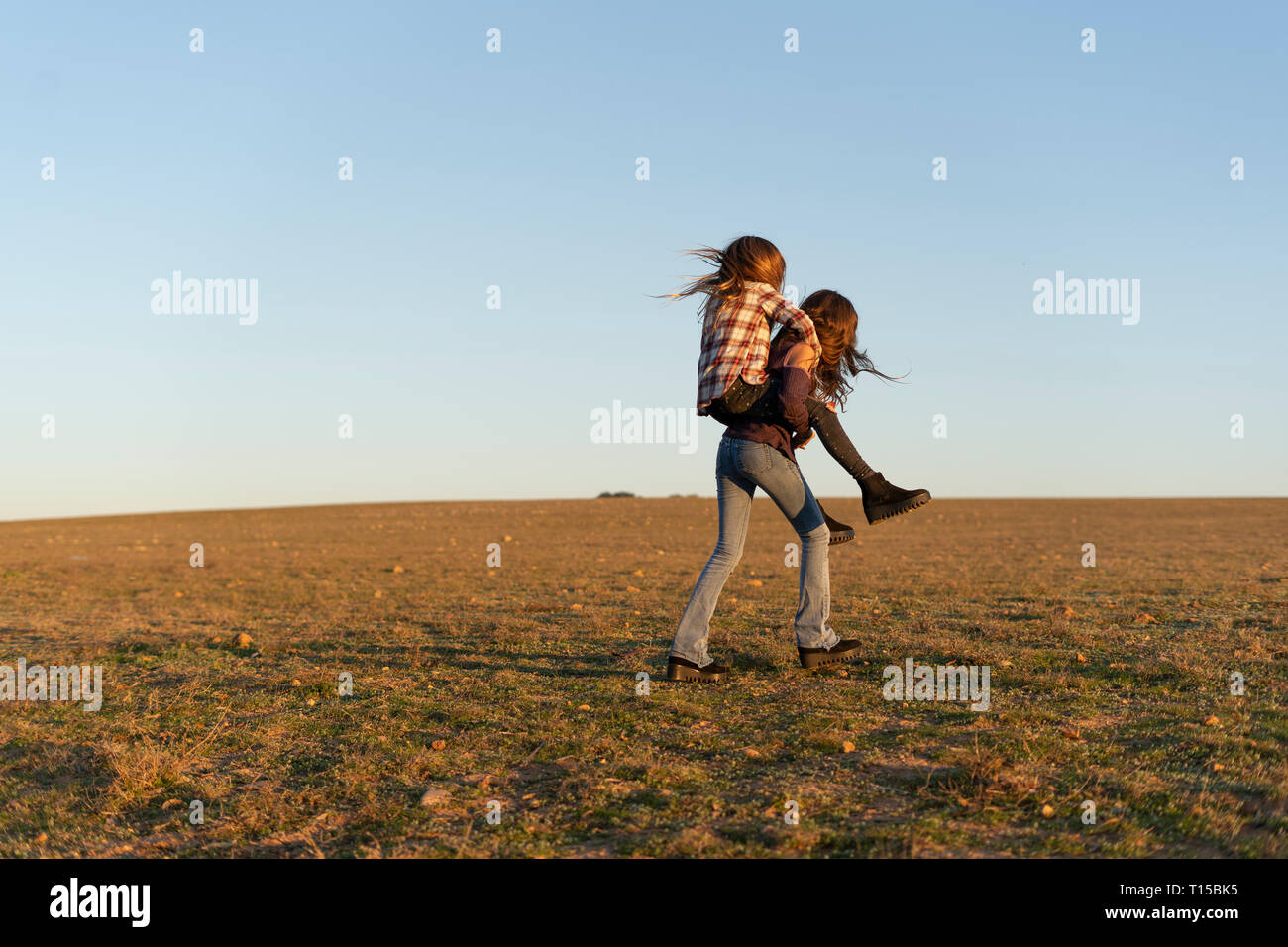 Girl giving her sister a piggyback ride outdoors Stock Photo - Alamy