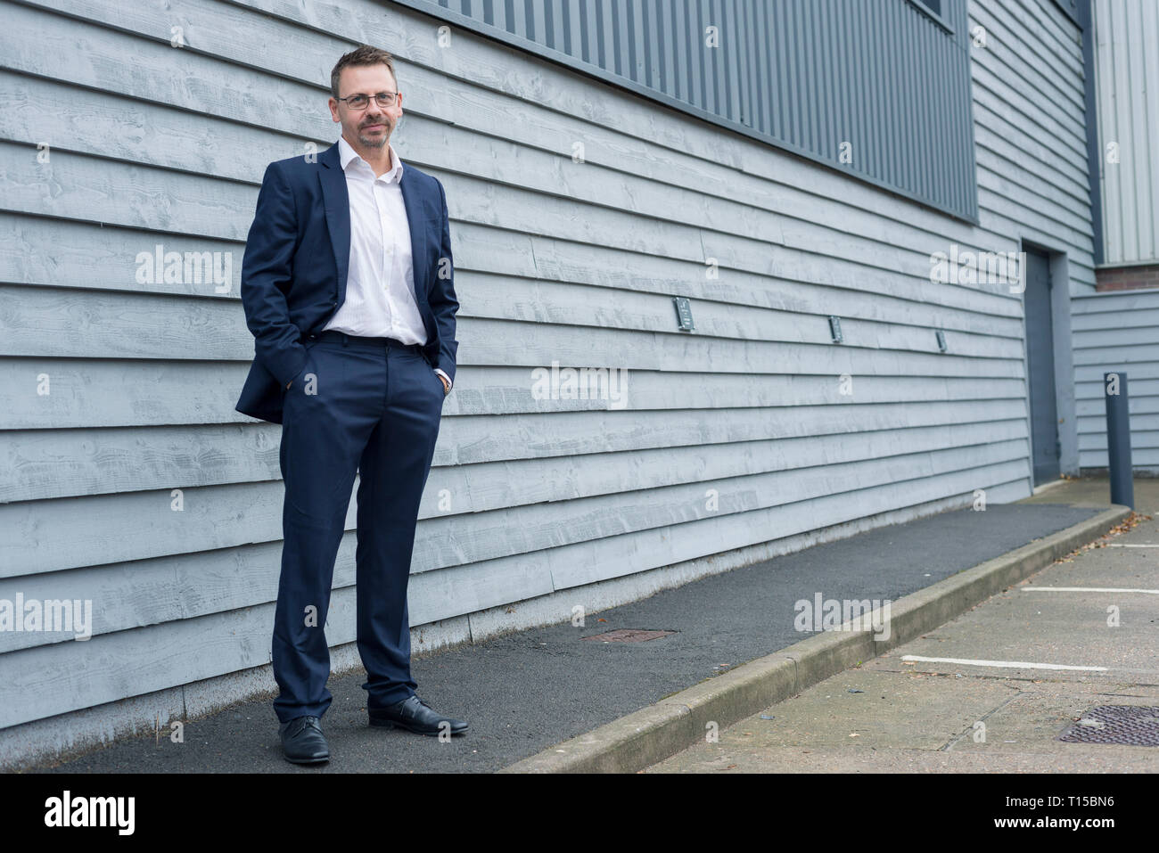 A businessman standing while wearing a suit and looking smart in a ...
