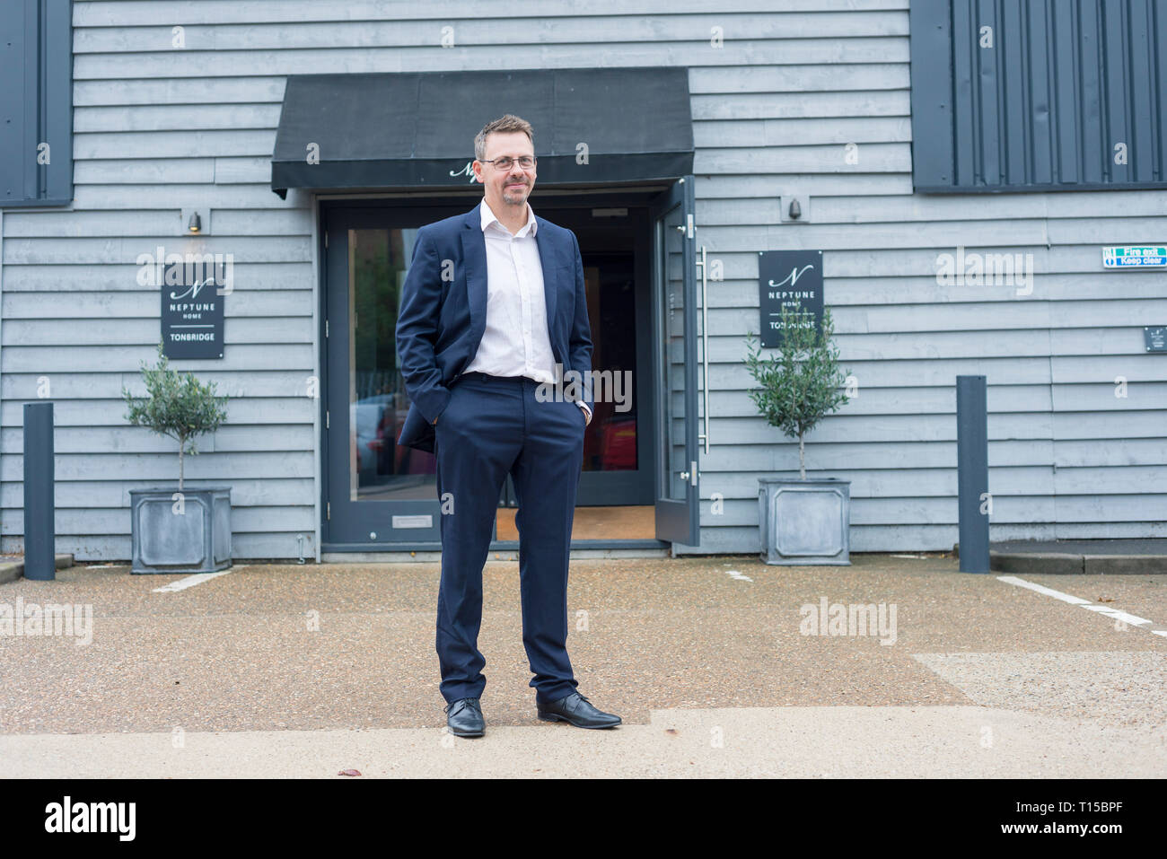 A businessman standing while wearing a suit and looking smart in a ...