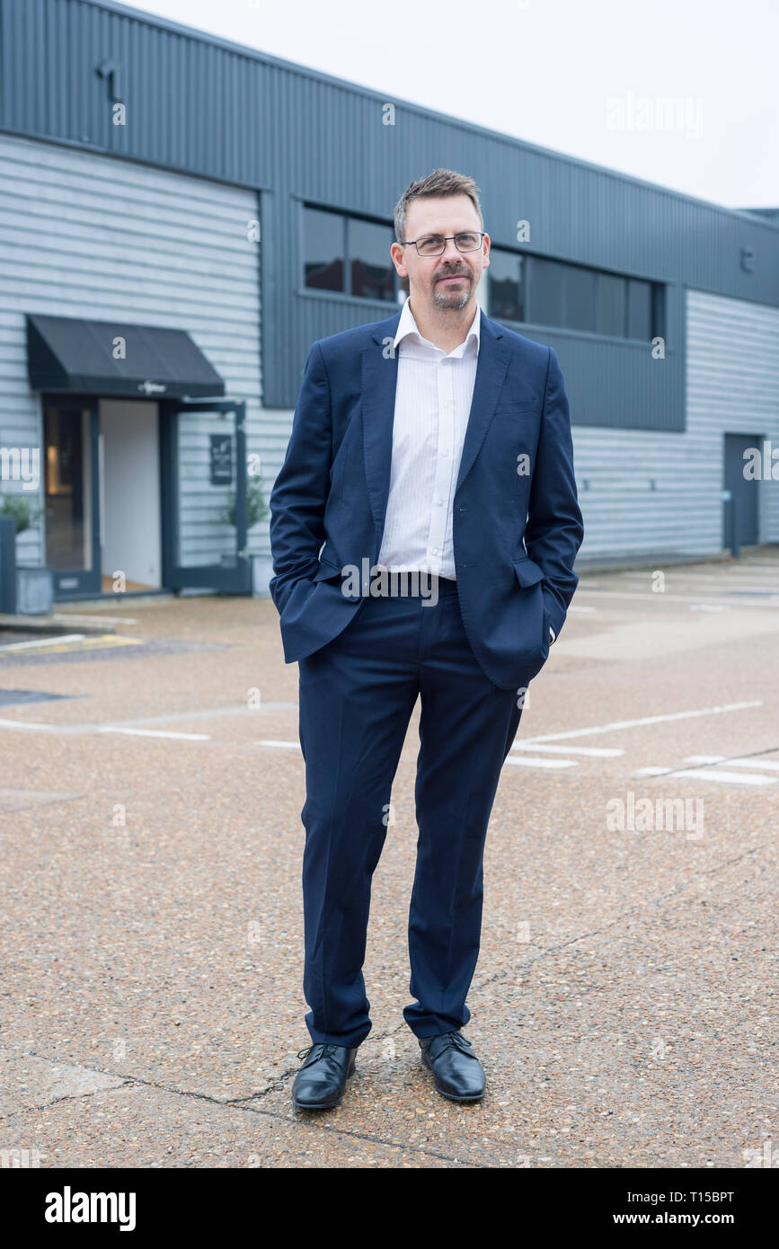 A businessman standing while wearing a suit and looking smart in a ...