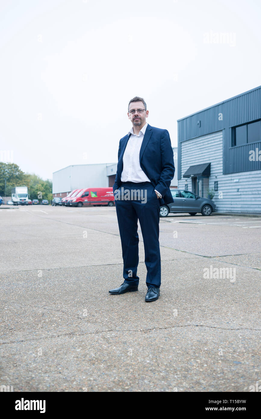 A businessman standing while wearing a suit and looking smart in a ...