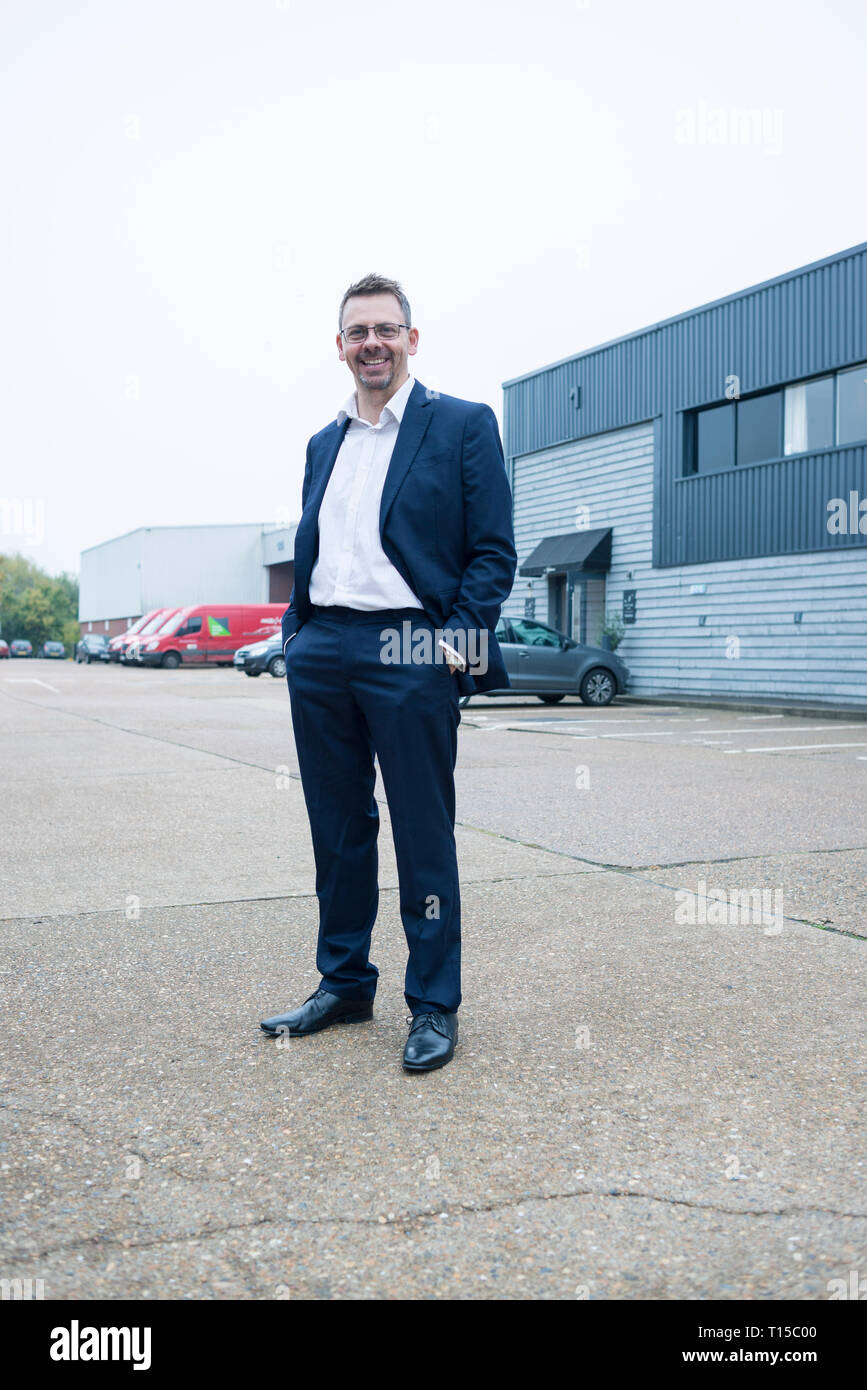 A businessman standing while wearing a suit and looking smart in a ...