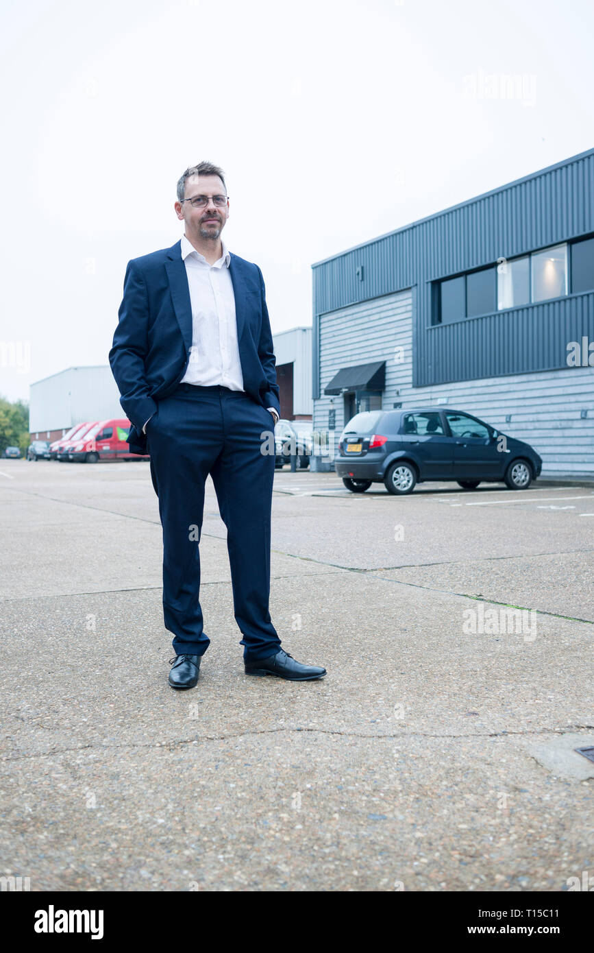 A businessman standing while wearing a suit and looking smart in a ...