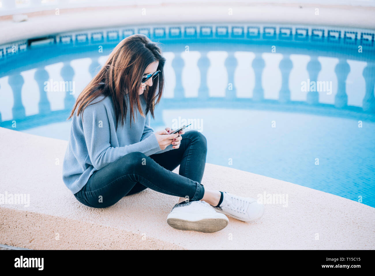 Woman using smartphone at swimming pool Stock Photo - Alamy