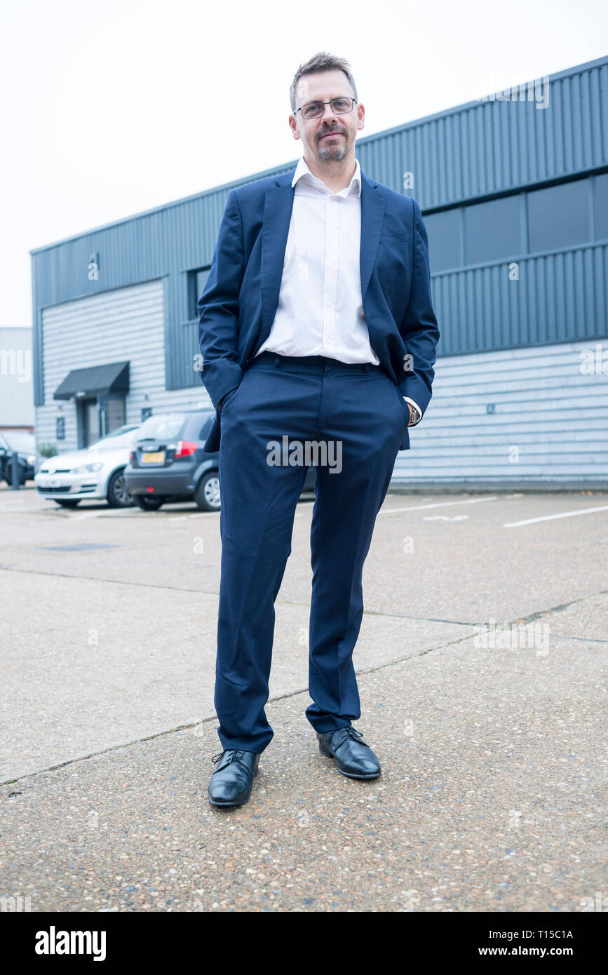 A businessman standing while wearing a suit and looking smart in a ...