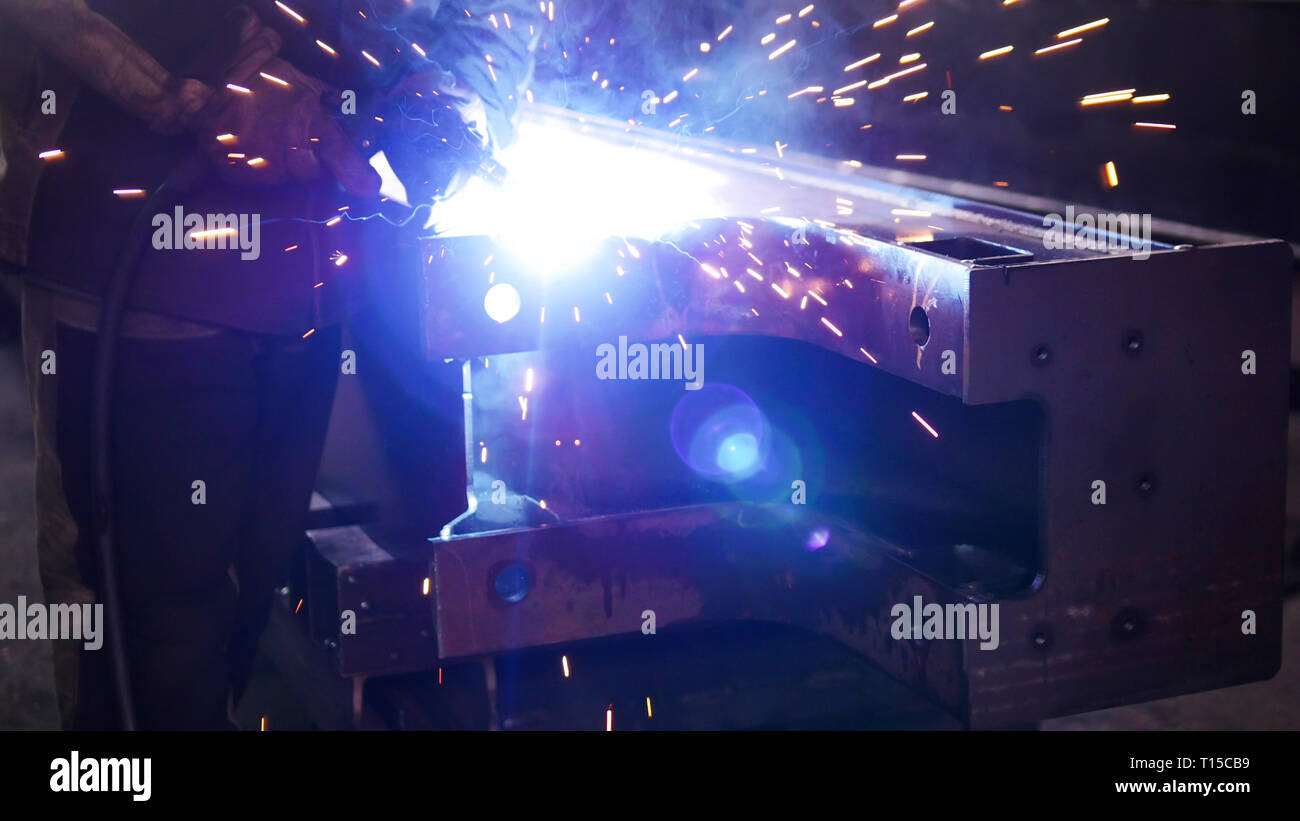 A man at the construction plant using a welding machine. Back view ...
