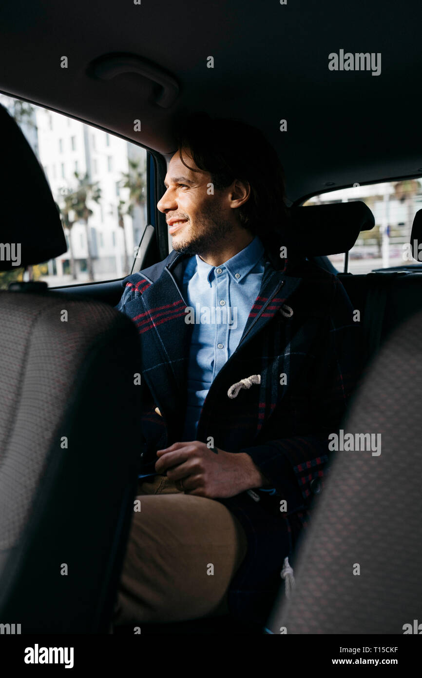 Smiling man sitting on back seat of a car looking out of window Stock ...