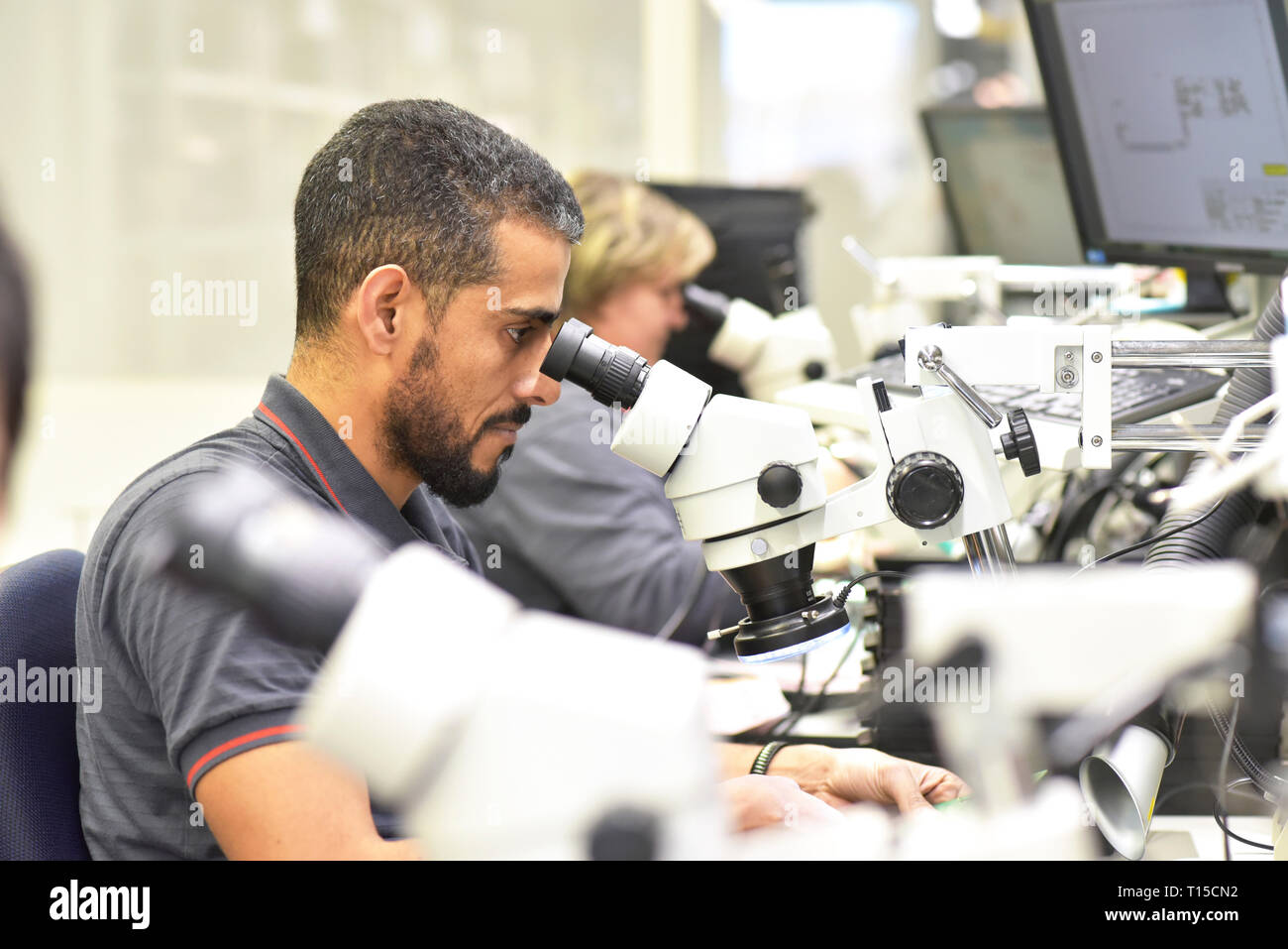 Man using a microscope for the quality control in the manufacturing of ...
