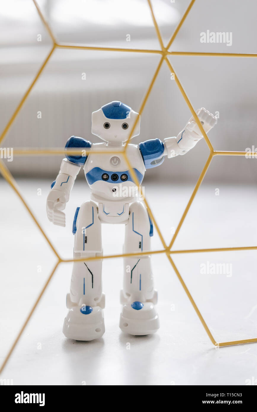 Miniature robot figurine standing behind structure Stock Photo - Alamy