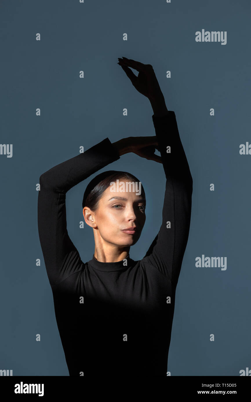 Portrait of woman dressed in black with flare on her face doing ...