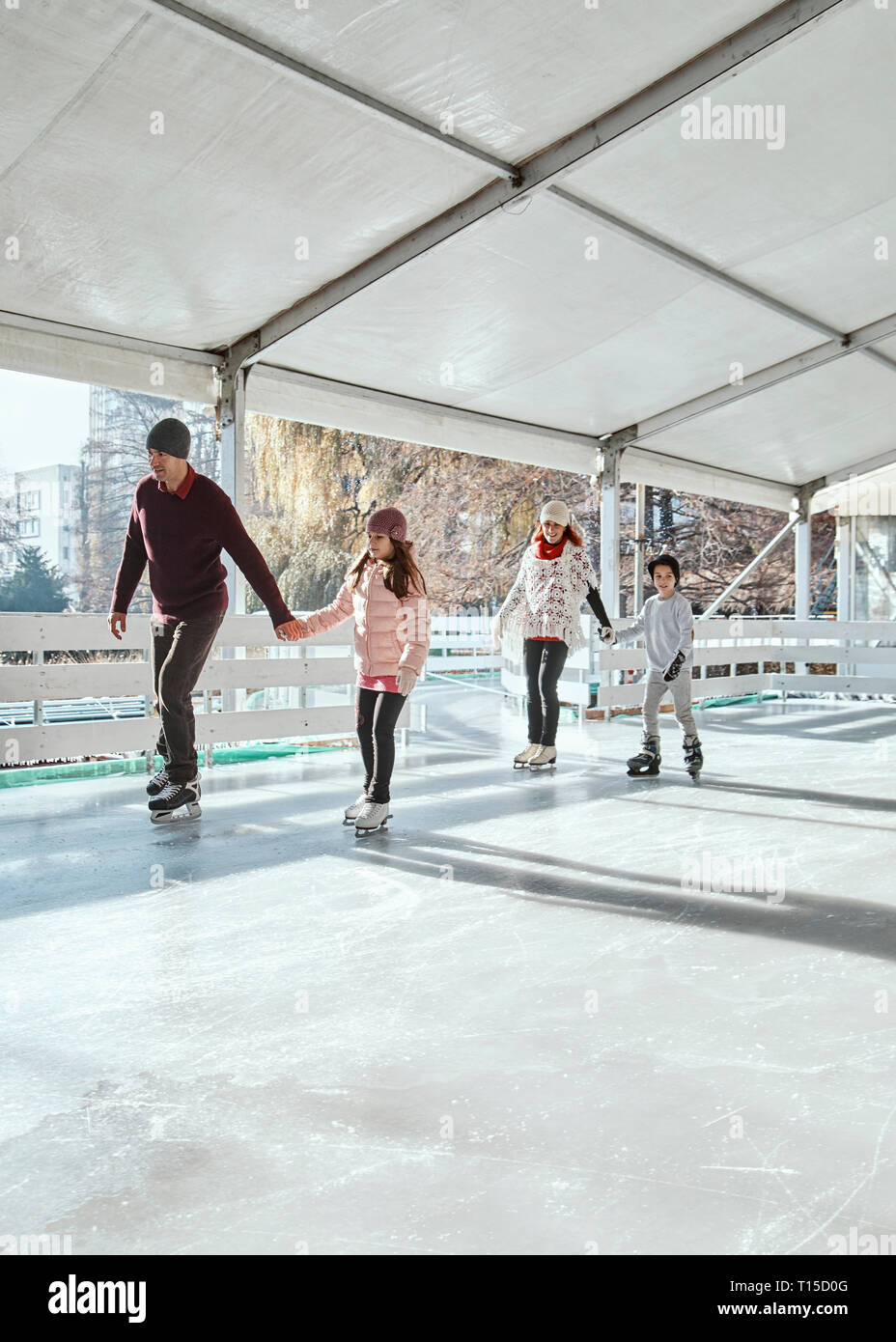 Family with two kids ice skating on the ice rink Stock Photo - Alamy