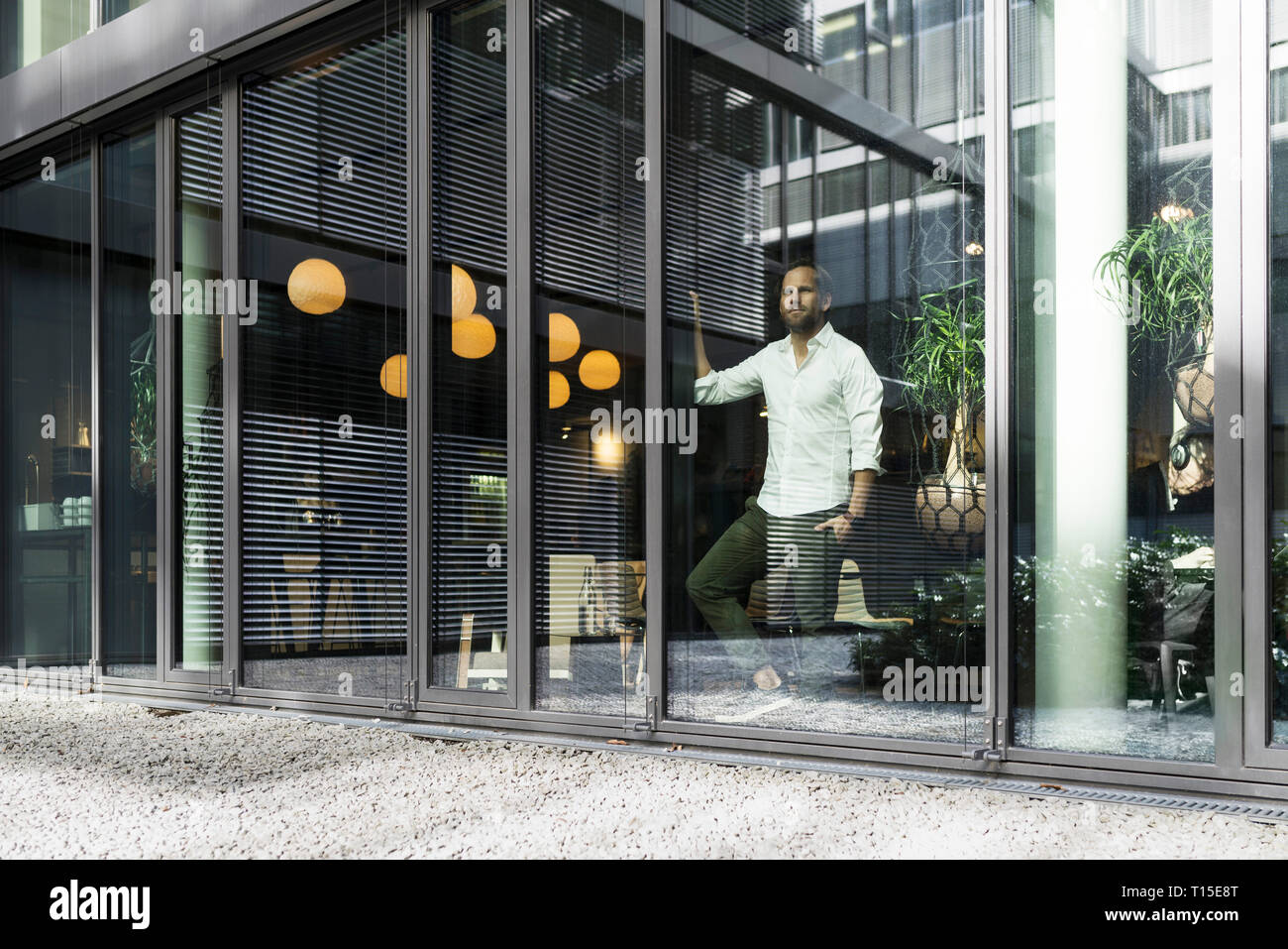 Pensative business man looking outside of large window front in modern ...